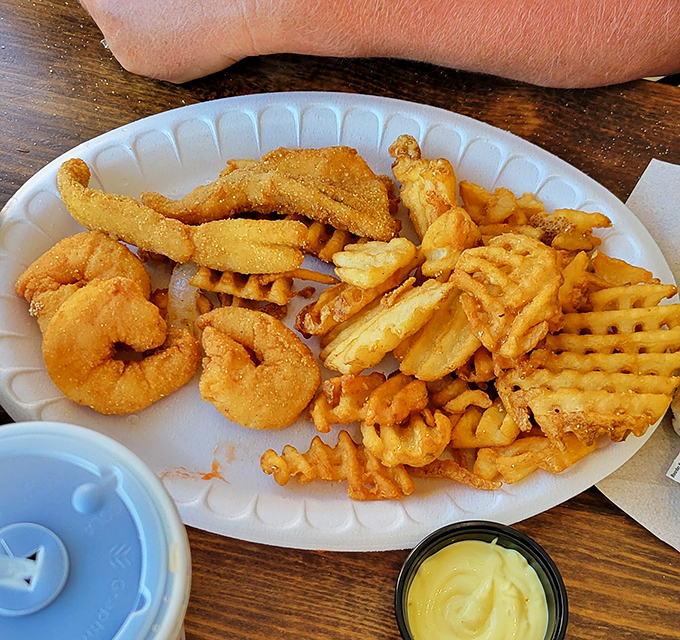 The seafood sampler plate&mdash;where indecision becomes a virtue. Crispy shrimp, golden perch, and waffle fries create the holy trinity of fried goodness.