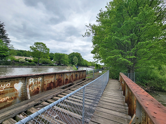 The footbridge spans water with that rustic industrial charm that says character without screaming "tetanus shot recommended."