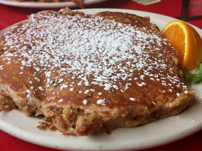 Powdered sugar falls like fresh snow on this golden griddle cake, proving that sometimes the simplest pleasures deliver the most profound satisfaction.