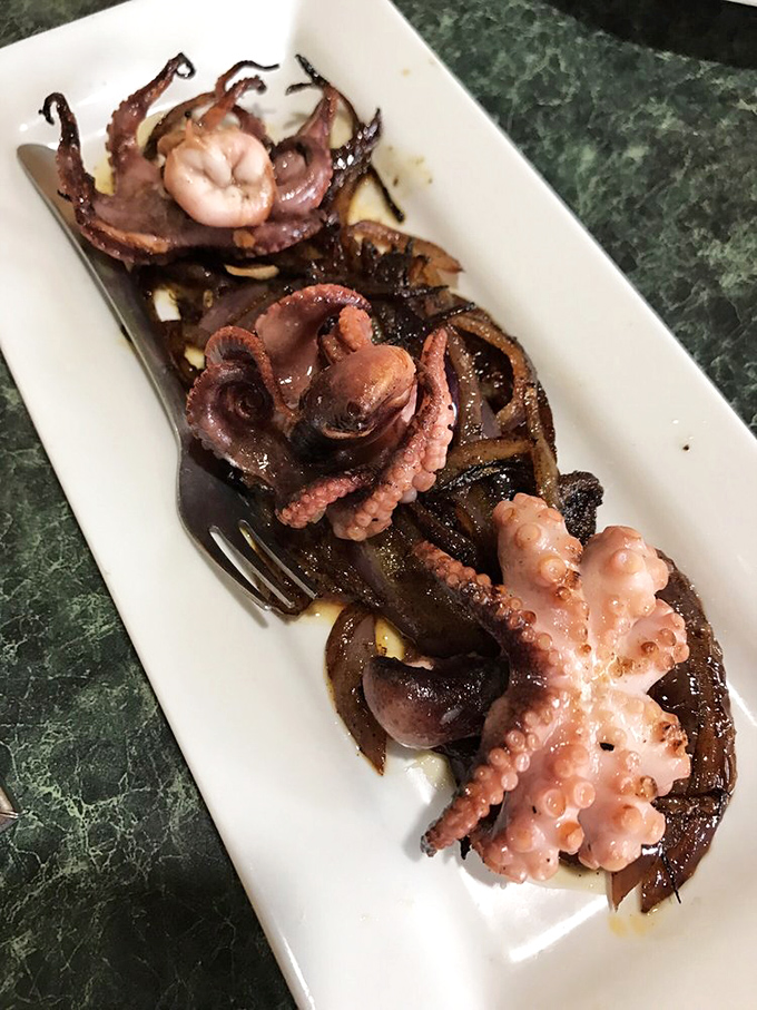 Charred baby octopus with grilled onions&mdash;tender, smoky, and proof that eight legs can be absolutely delicious on your fork.