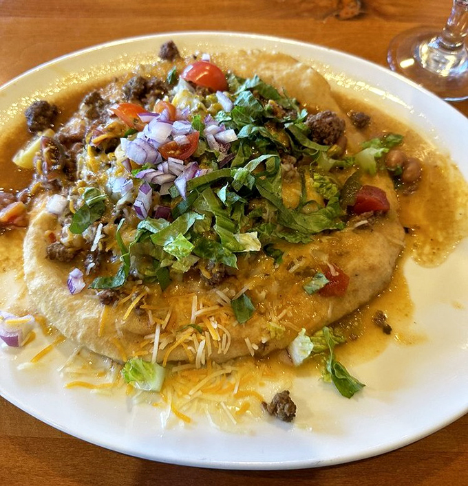 The Indian Taco isn't just food&mdash;it's edible architecture. A golden fry bread foundation supports layers of savory goodness topped with garden-fresh garnishes.