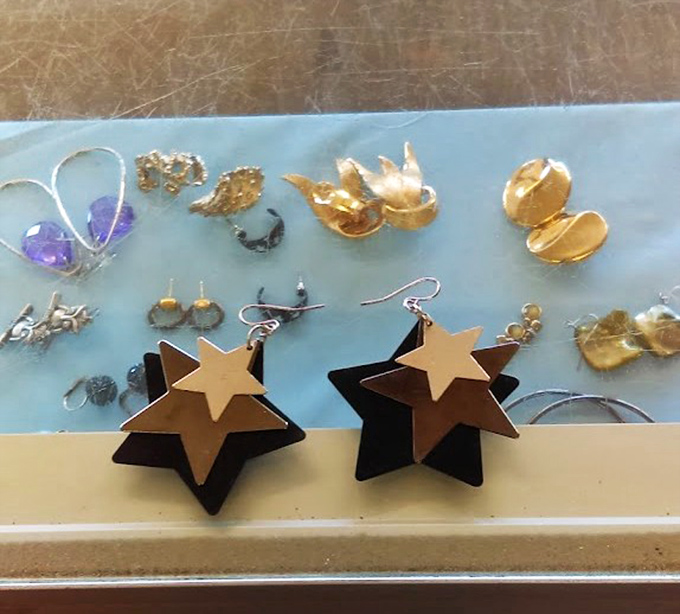 Star-shaped earrings and vintage brooches glimmer under display case lights, waiting to become someone's statement piece.