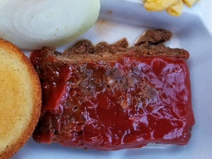 Meatloaf glazed with tangy sauce sits alongside cornbread and sides &ndash; a plate that whispers "comfort" in the universal language of home cooking.