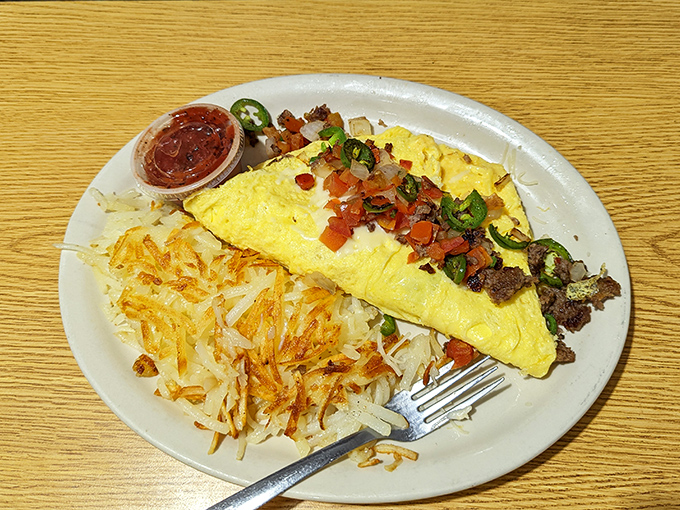 This omelet doesn't just contain ingredients; it showcases them like a culinary red carpet, with hash browns playing the essential supporting role.