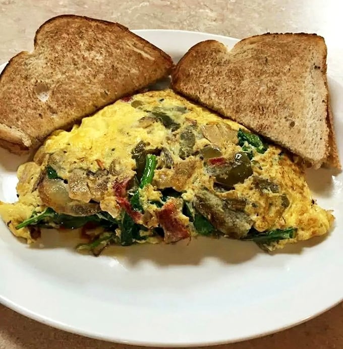 An omelet that's practically a geological expedition of flavors &ndash; layers of vegetables, cheese, and meat that would make any breakfast enthusiast weep with joy.