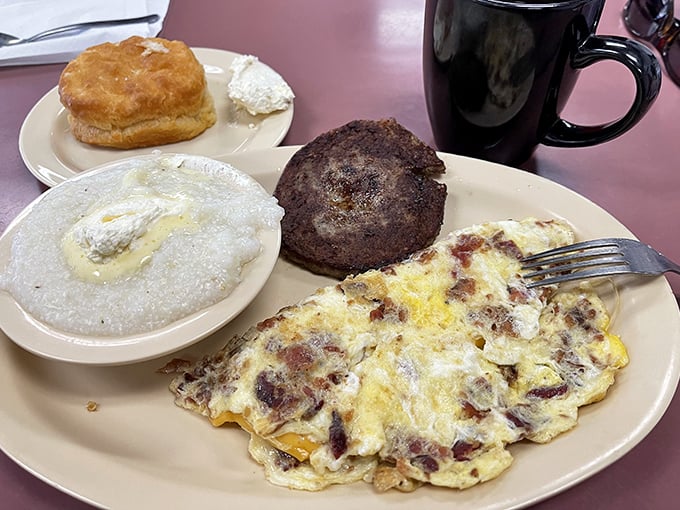 A breakfast symphony on a plate: fluffy eggs, savory meat, buttery grits, and a biscuit that would make your grandmother nod in approval.