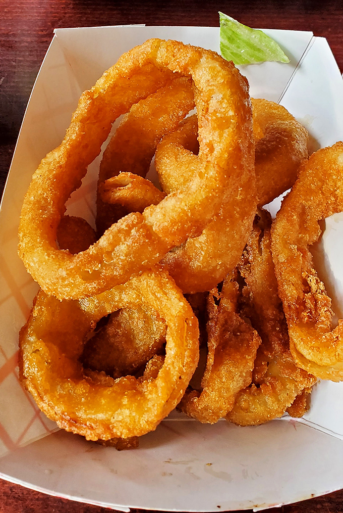 Golden onion rings stacked like delicious life preservers &ndash; crispy, substantial, and guaranteed to disappear from the table faster than you can say "just one more."
