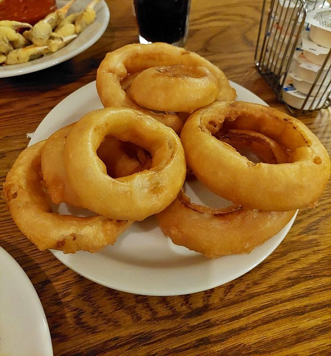 Golden onion rings stacked like delicious life preservers, ready to rescue you from ordinary appetizers with their crispy perfection.