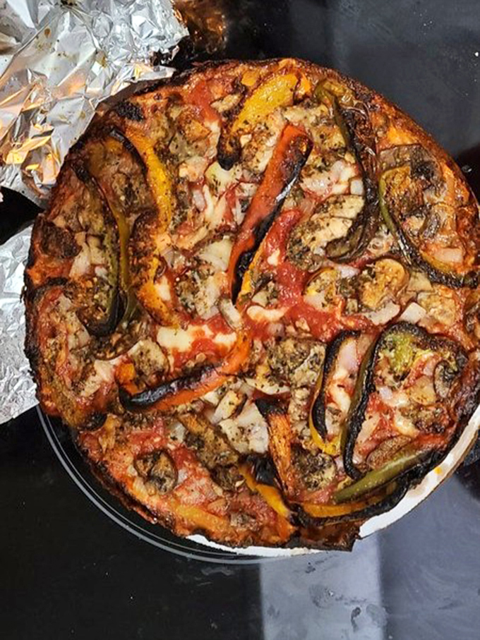 Another pizza masterpiece emerges from the oven, where vegetables maintain their character and that legendary crust develops its signature char.