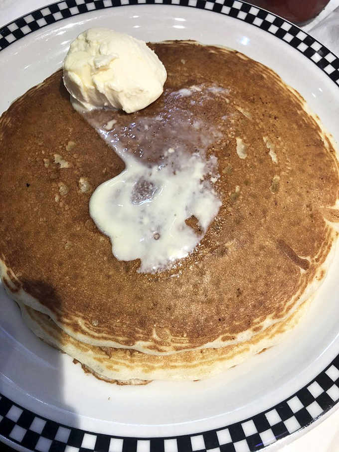 Pancakes so perfectly golden they could win medals, with butter melting into their fluffy depths like a warm embrace.