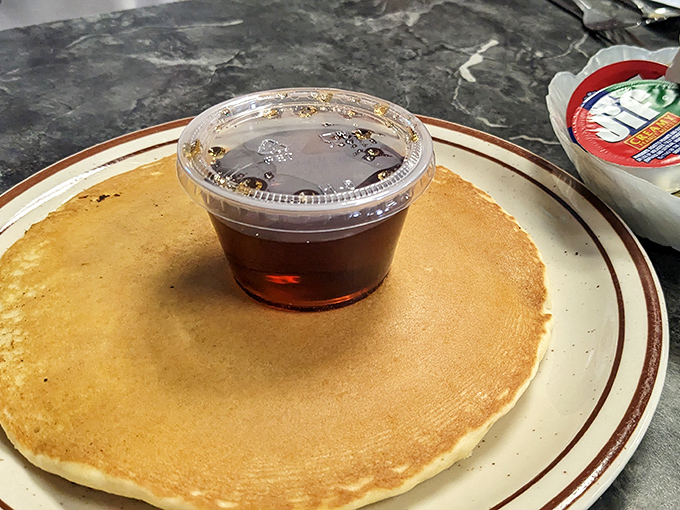The pancake that launched a thousand satisfied sighs—perfectly golden, plate-sized, and just waiting for that maple syrup to create breakfast magic.