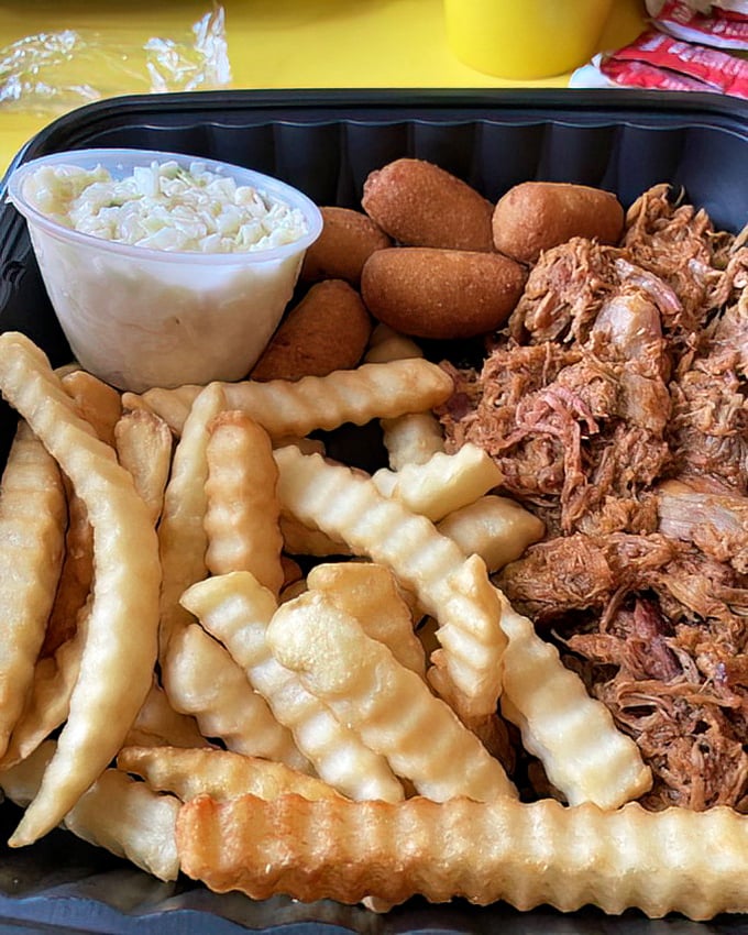The barbecue trifecta &ndash; pulled pork, crispy fries, and hush puppies with slaw &ndash; a Southern symphony on a single tray.