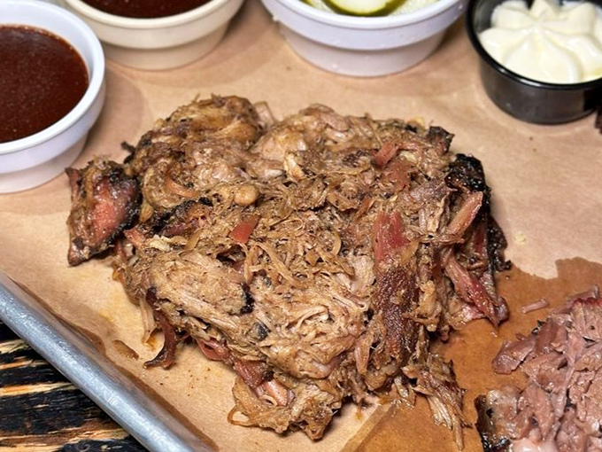 Pulled pork so tender it practically surrenders to your fork, with sauce containers standing by like eager accomplices.