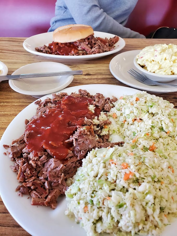 A mountain of pulled pork beside a landscape of cole slaw. In the background, someone's already halfway to BBQ bliss.