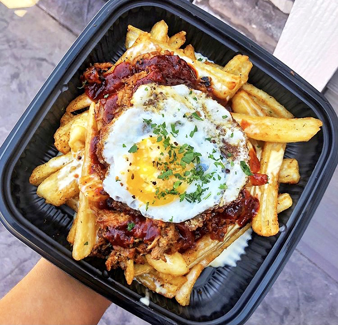 Pulled pork poutine loaded with crispy fries that require a fork, napkins, and possibly a signed waiver. That sunny-side-up egg is the crown jewel of this magnificent mess.