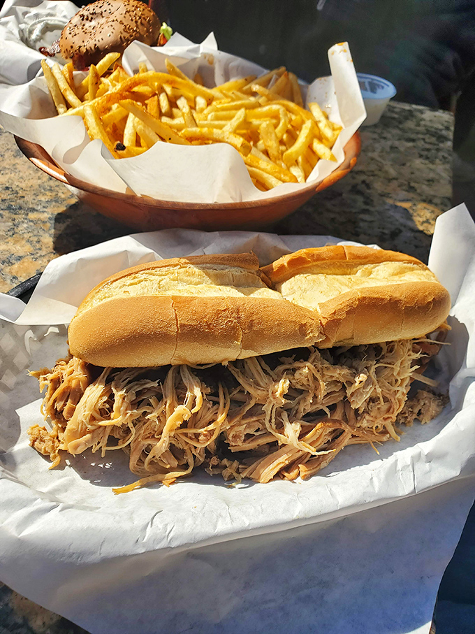 The pulled pork sandwich arrives like a delicious challenge to your jaw's structural integrity.