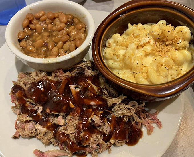 The holy trinity of barbecue perfection: pulled pork with sauce that glistens, mac and cheese that bubbles, and baked beans that have clearly been given proper attention.