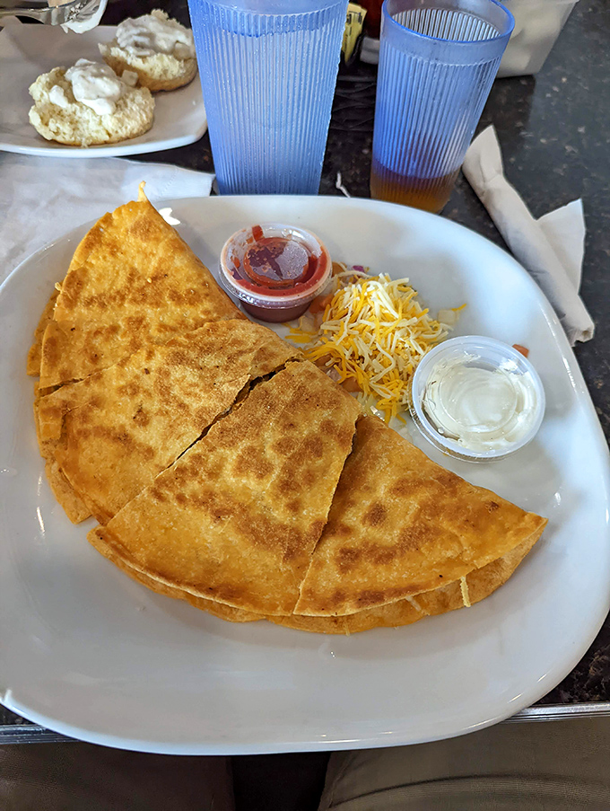 This quesadilla isn't playing games&mdash;golden-crisp tortilla, melty cheese, and those little cups of sour cream and salsa standing by like loyal sidekicks.