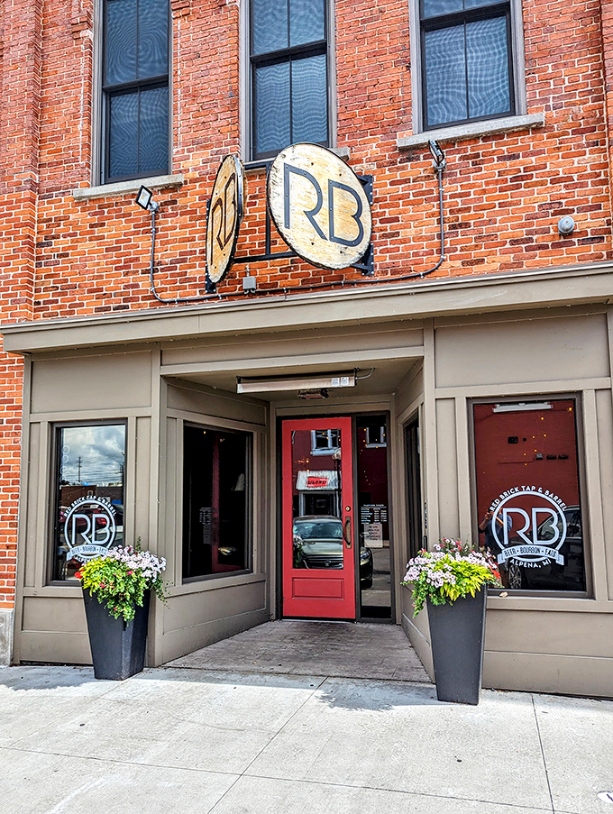 The Red Brick Tap & Barrel welcomes visitors with its warm red door and flourishing planters&mdash;the universal signal for "good times and local brews inside."