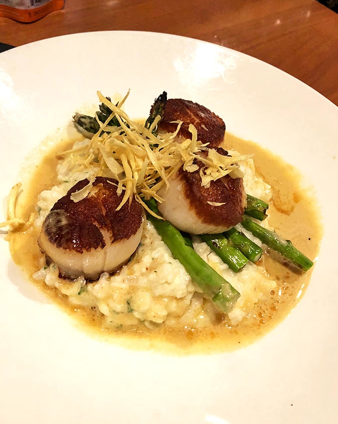 Perfectly seared scallops nestled on creamy risotto with asparagus&mdash;proof that seafood this far from an ocean can still make waves.