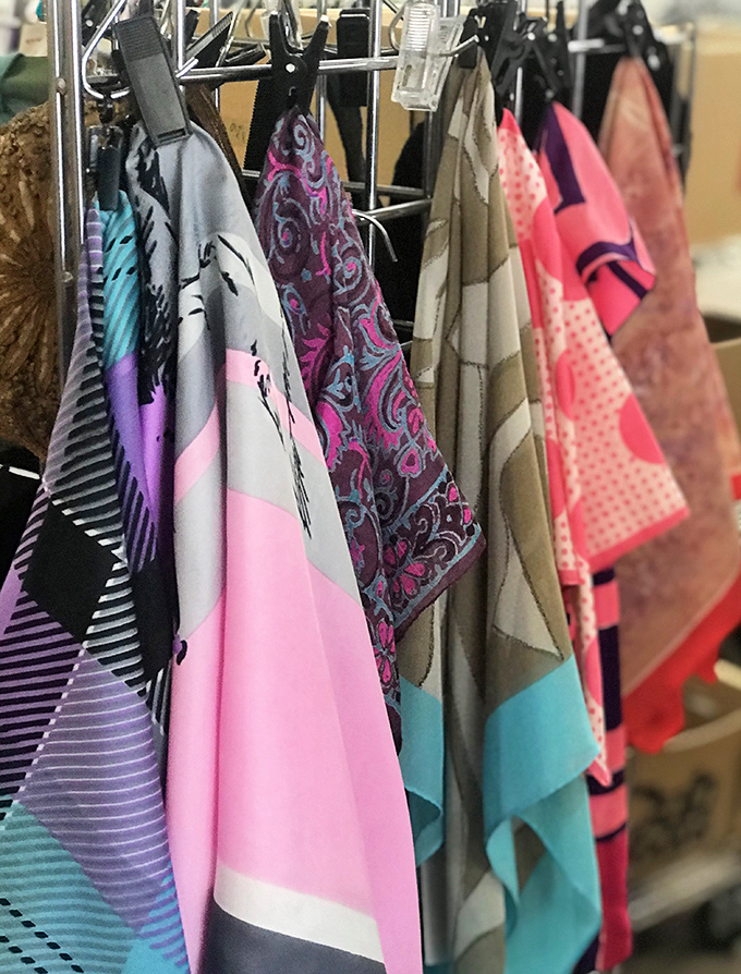 Silk whispers and cotton conversations hang in delicate rows. These scarves tell fashion stories spanning decades, each pattern a chapter in style history.