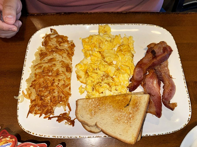 The holy trinity of breakfast&mdash;crispy hash browns, fluffy scrambled eggs, and bacon&mdash;assembled with the precision of a master craftsman.