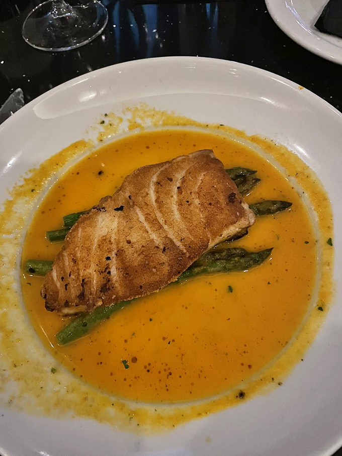 Who needs land when the sea offers treasures like this perfectly seared fish resting on asparagus islands in a buttery ocean?