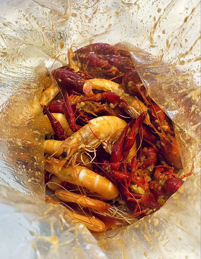A clear plastic bag reveals a treasure trove of crawfish and shrimp, swimming in spiced sauce &ndash; seafood boils don't get more authentic than this.