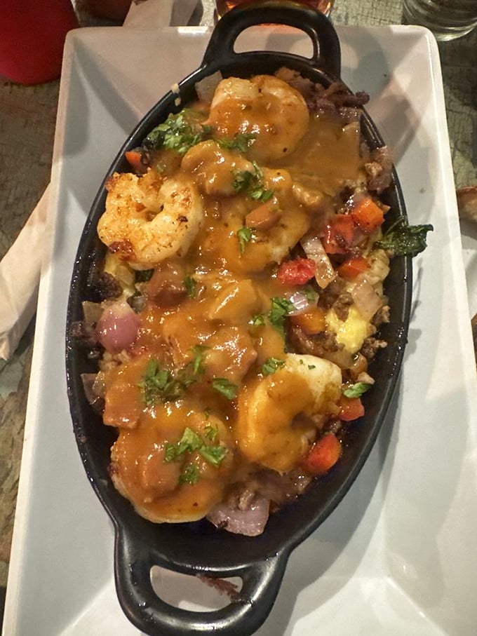 Shrimp and grits in a sizzling skillet with vegetables and sauce proves coastal cuisine belongs everywhere, including landlocked Greensboro.