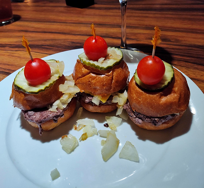 These aren't just sliders &ndash; they're miniature flavor bombs, each one topped with a cherry tomato like a tiny edible party hat.
