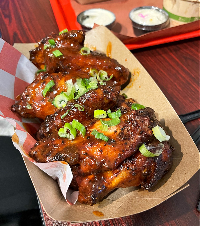Wings that have clearly graduated summa cum laude from Barbecue University, their crispy, sauce-slathered glory garnished with fresh scallions.