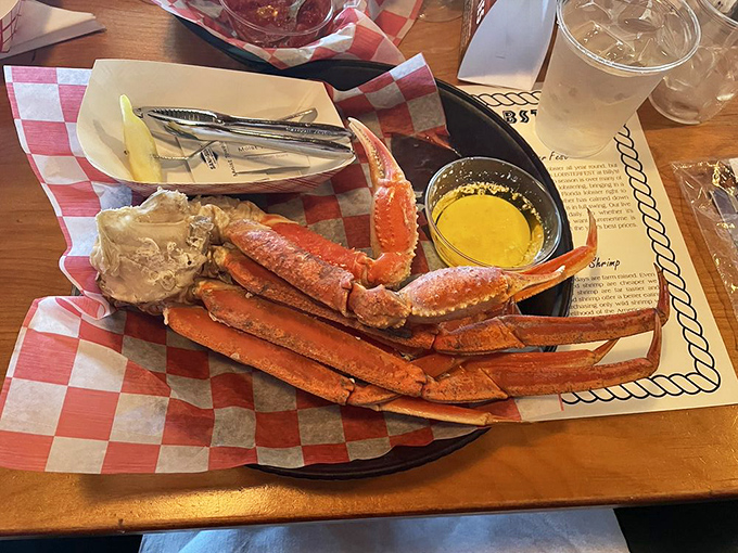 Snow crab legs sprawled across red-checkered paper &ndash; nature's puzzle that rewards patience with sweet, tender meat.