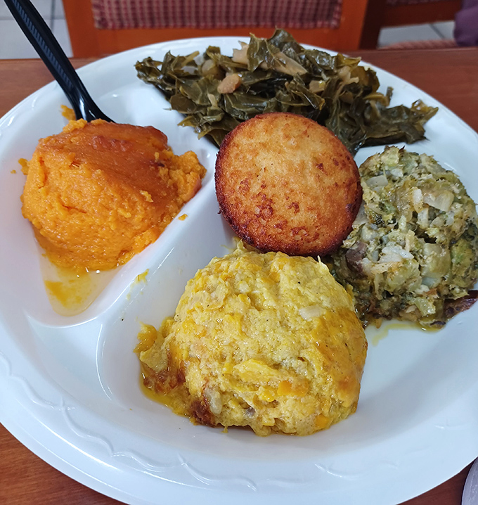 The vegetable plate that converts vegetable skeptics – sweet potato soufflé, cornbread, and collard greens proving sides are never an afterthought here.