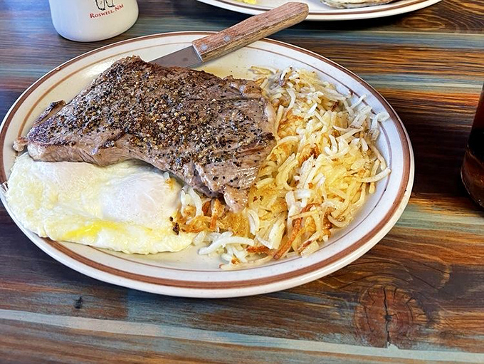 That T-bone steak covers the plate like it's claiming territory, with eggs standing guard over hash browns below.