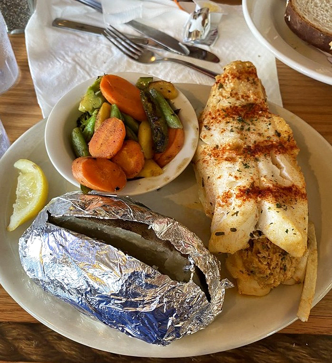 The stuffed orange roughy shares a plate with colorful vegetables and a foil-wrapped potato—a trio that would make Neptune himself put down his trident for a bite.