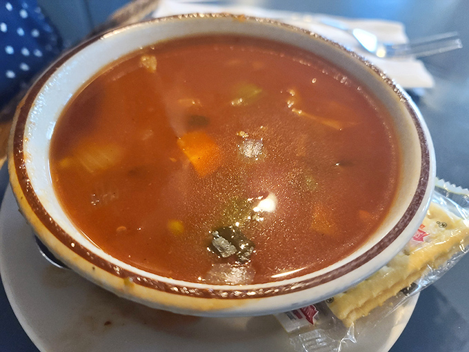 A steaming bowl of vegetable soup that looks like it simmered all day while someone's grandmother whispered encouragement to each carrot and potato.