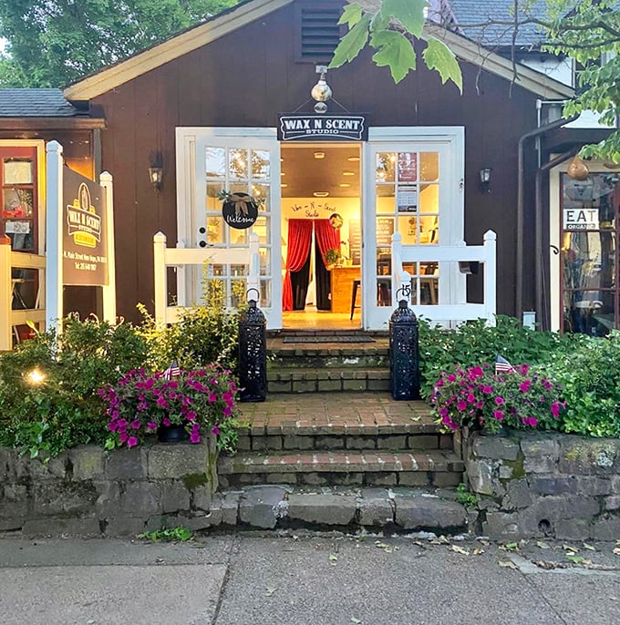 Wax N Scent Studio's charming cottage exterior, with its vibrant flowers and white picket fence, practically whispers "come in and create something wonderful."