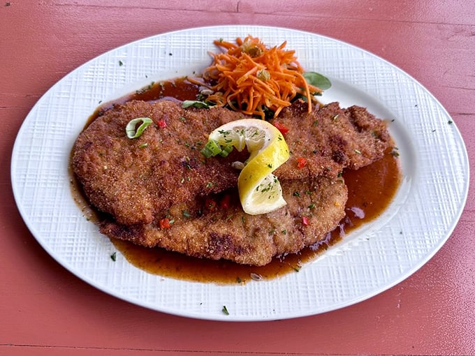 The Wiener Schnitzel sprawls majestically across the plate like a golden-brown landscape, with that essential lemon wedge standing by for duty.