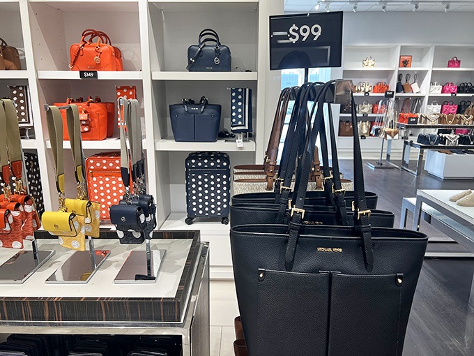 Michael Kors bags arranged with museum-worthy precision, each one whispering sweet nothings to your credit card.