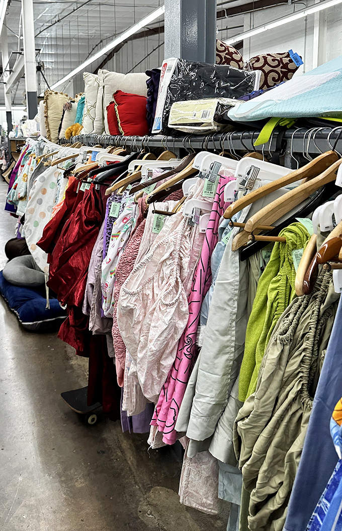 A rainbow of fabrics cascades from racks, with pillows perched above like fluffy sentinels. Bedding paradise or textile waterfall? You decide.