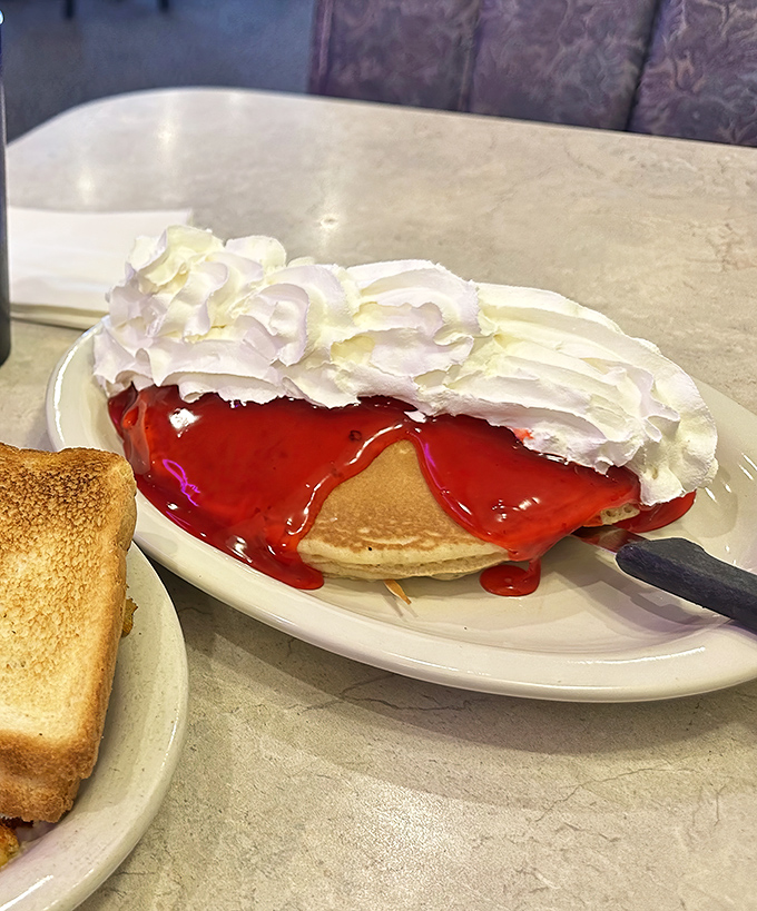 These pancakes aren't just topped with strawberry glaze&mdash;they're wearing a red carpet outfit. The whipped cream is just showing off at this point.