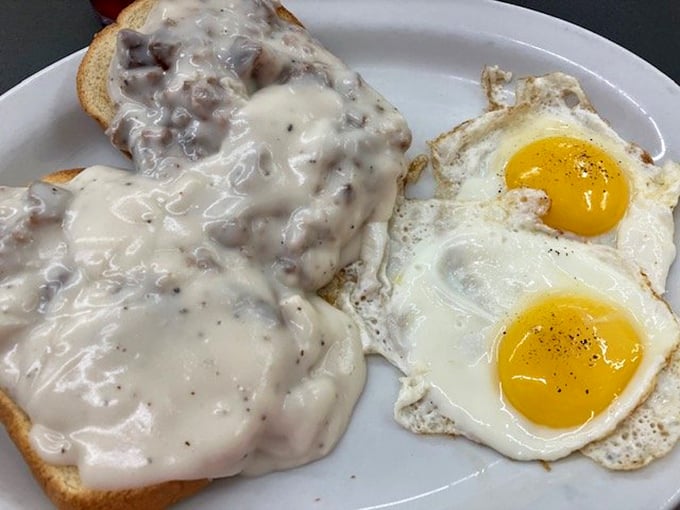 The holy grail of Southern breakfast: creamy sausage gravy cascading over toast alongside perfectly sunny-side-up eggs that wink at you.
