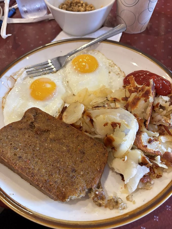 Two sunny-side up eggs staring back at you like old friends, alongside home fries that have achieved that perfect crispy-to-tender ratio.