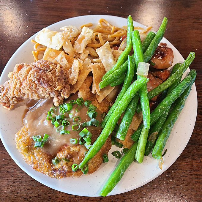The art of buffet plate arrangement rivals Olympic tetris&mdash;crispy chicken, noodles, and vibrant green beans competing for precious real estate.