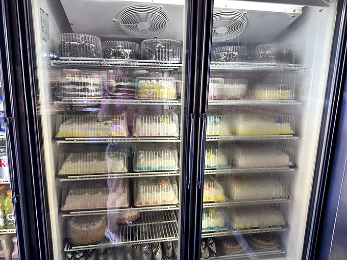 The refrigerated cake display&mdash;where birthdays, anniversaries, and "I'm sorry I forgot our anniversary" celebrations begin their journey to redemption.