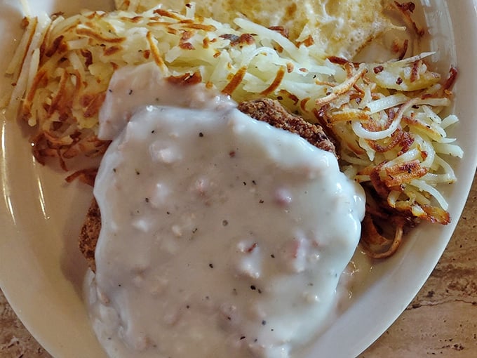 Comfort food perfection: chicken fried steak smothered in peppery gravy alongside hash browns crisped to golden perfection.