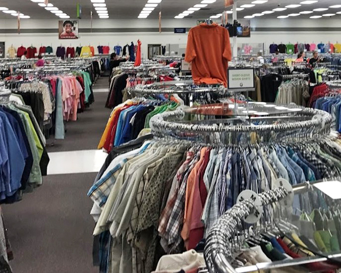 Circular racks create a textile forest where button-downs and blouses hang like colorful leaves, waiting for their next season in someone's wardrobe.