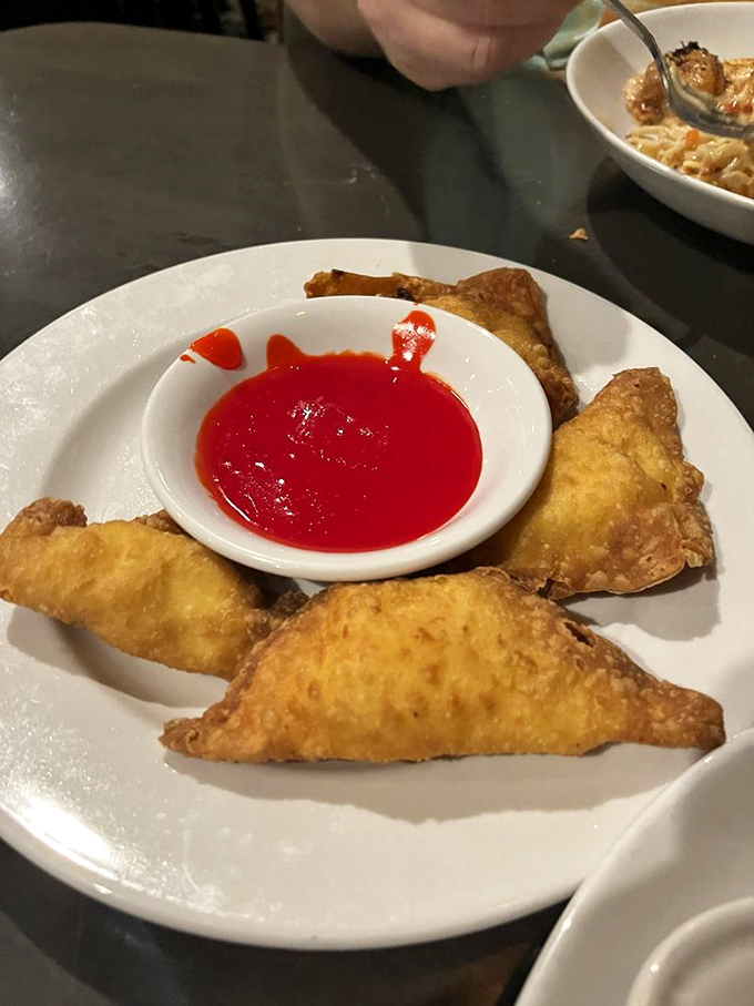 Crab rangoon triangles with that perfect golden crunch, waiting to reveal their creamy treasure. The dipping sauce is just showing off.
