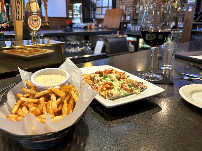 Bar dining done right&mdash;crispy fries, a flatbread that demands attention, and a glass of red that's saying "slow down, savor this moment."