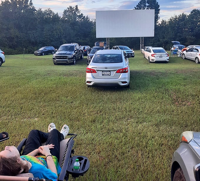 As twilight settles in, the drive-in transforms into a community of relaxed moviegoers, some already reclining in perfect viewing position.